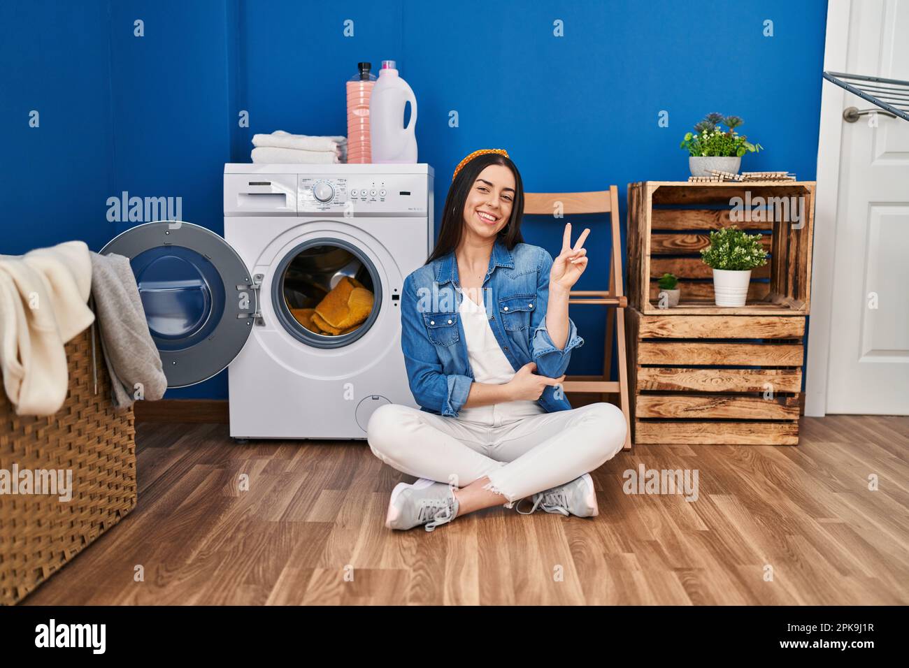 Hispanic woman doing laundry sitting on the floor smiling with happy ...