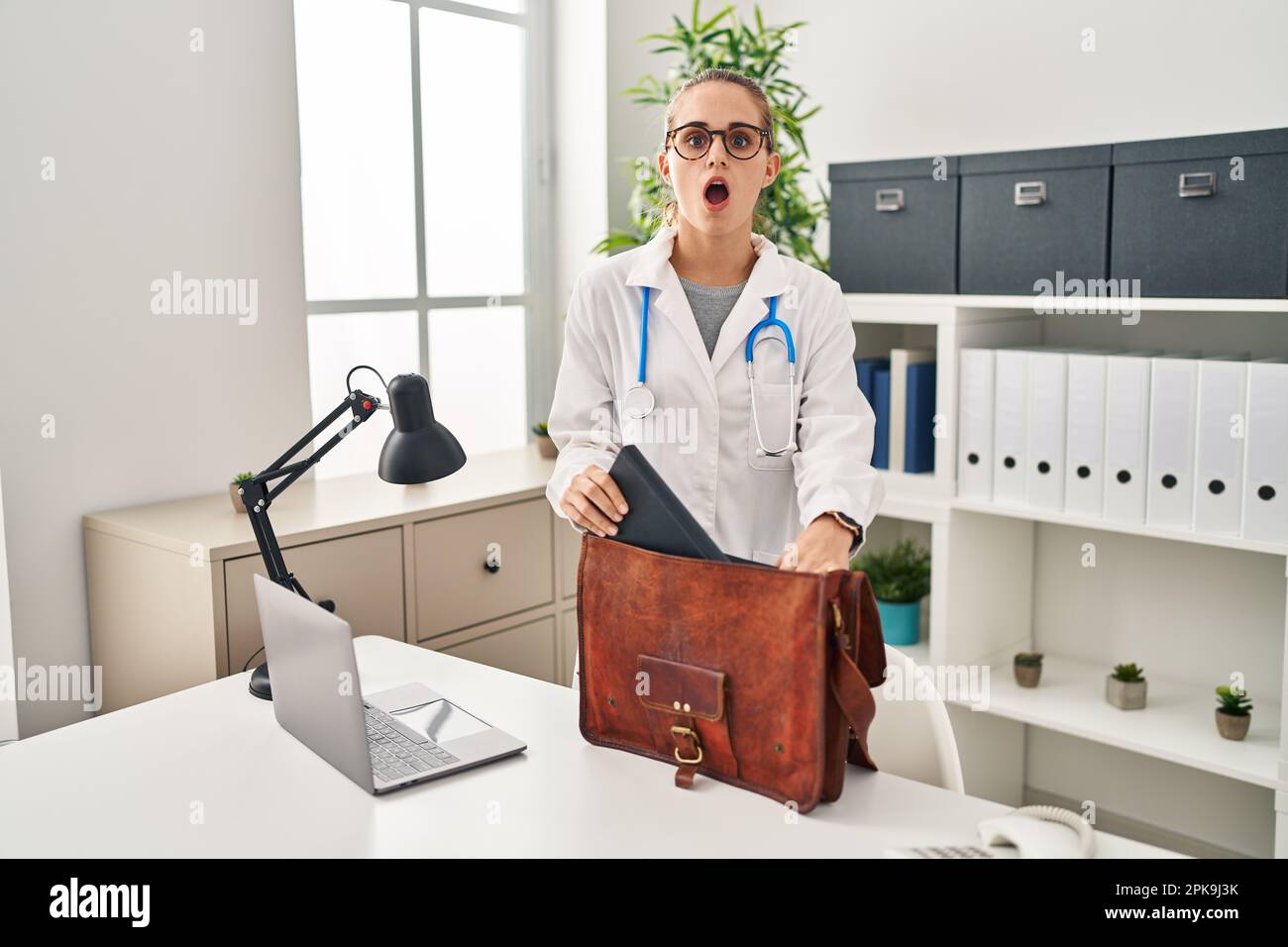 Young doctor woman at the clinic afraid and shocked with surprise and ...