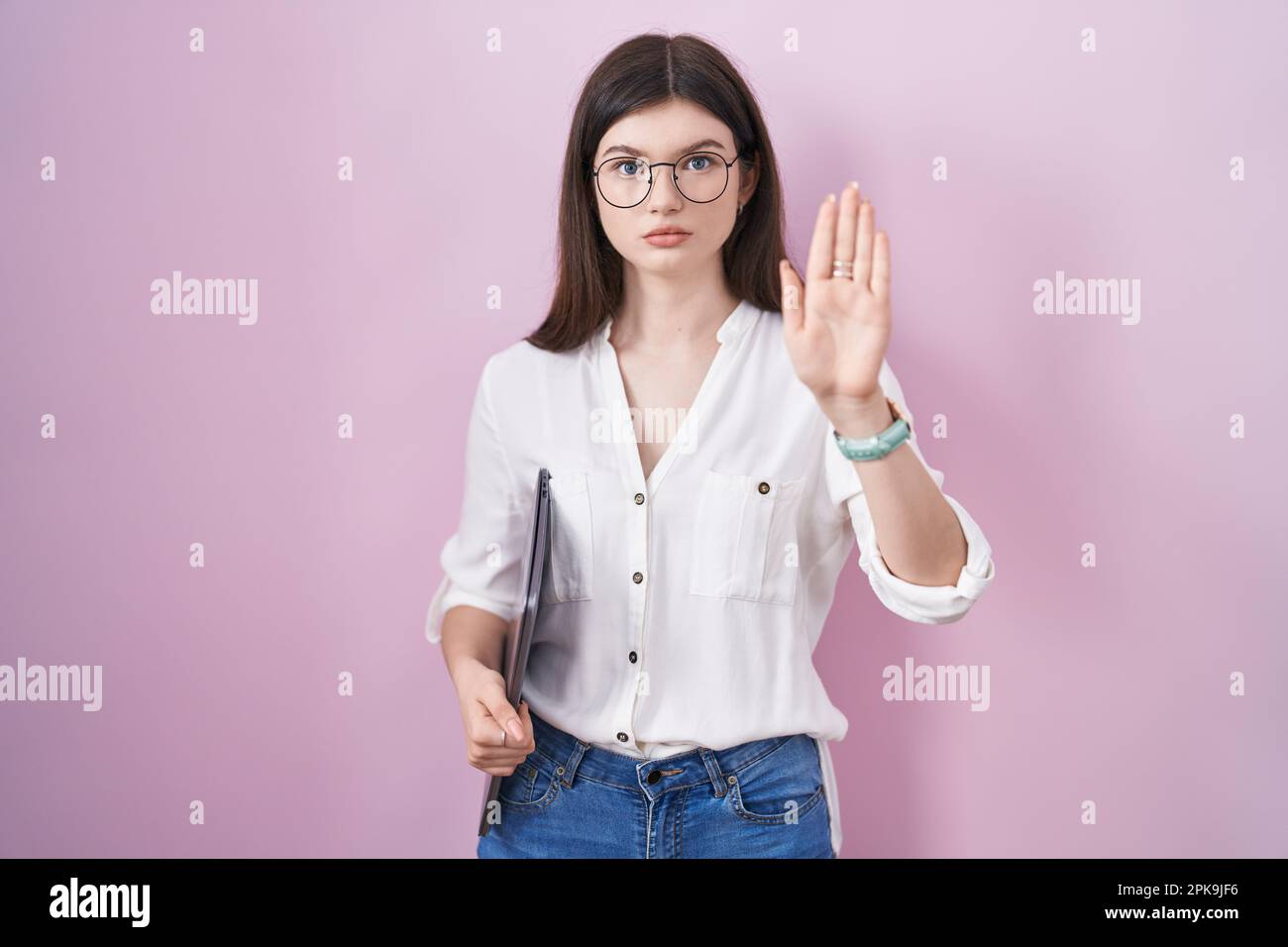 Young caucasian woman holding laptop doing stop sing with palm of the ...