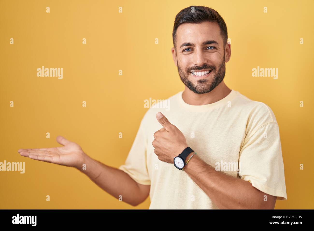 Handsome hispanic man standing over yellow background showing palm hand ...
