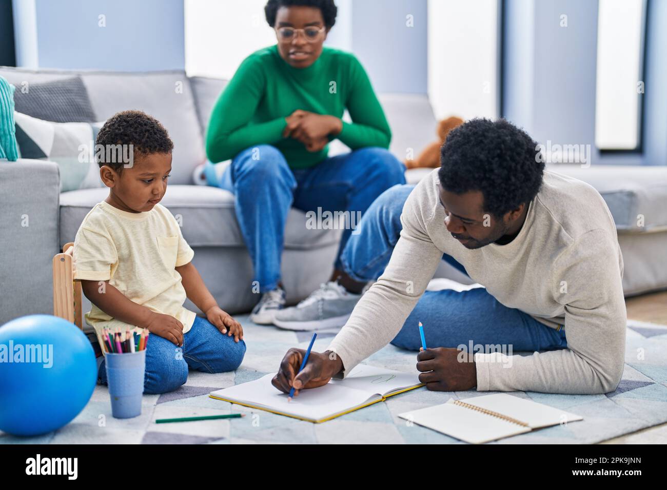 African american family drawing on notebook sitting on floor at home ...
