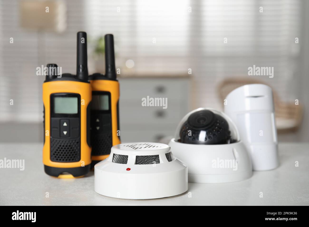 Walkie talkies, CCTV camera, smoke and movement detectors on white table indoors. Home security ...