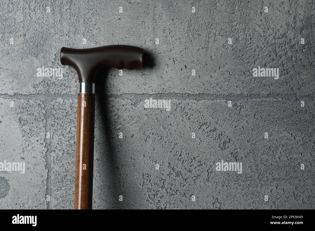 Elegant walking cane on grey stone background, closeup. Space for text ...