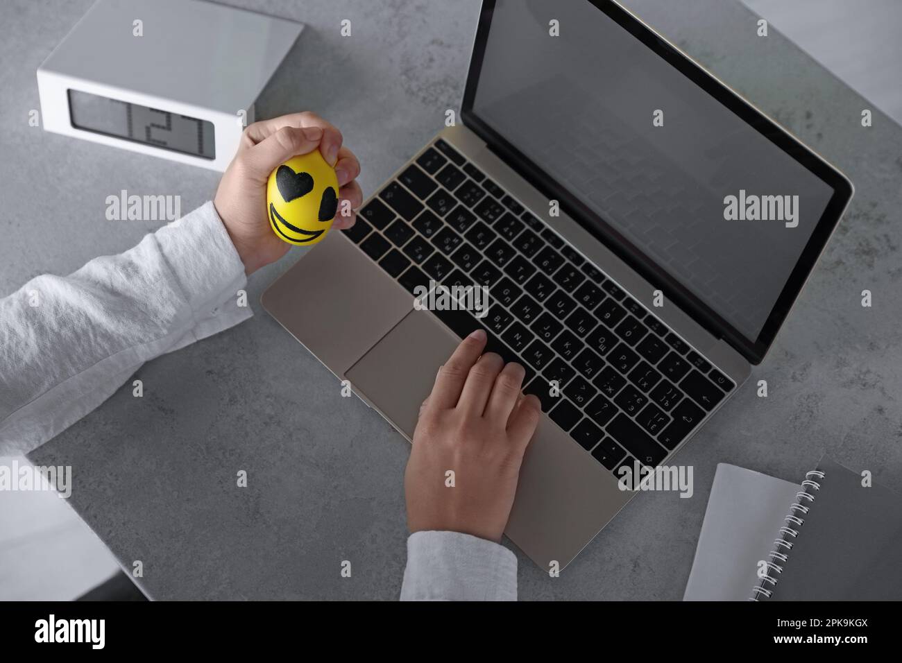 Woman squeezing antistress ball while working on laptop at table, above ...