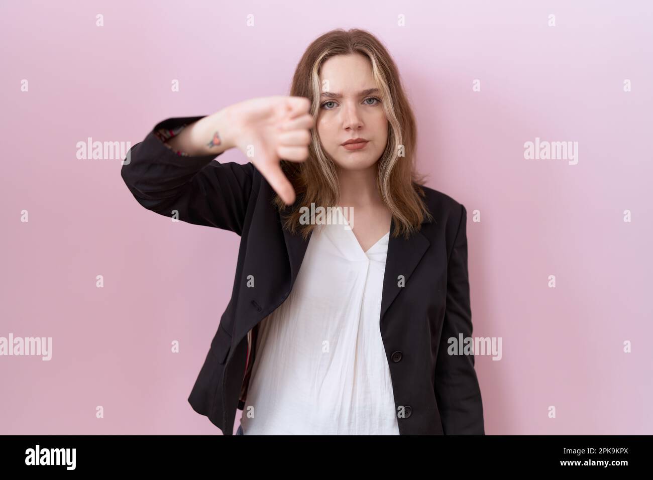 Young caucasian business woman wearing black jacket looking unhappy and ...