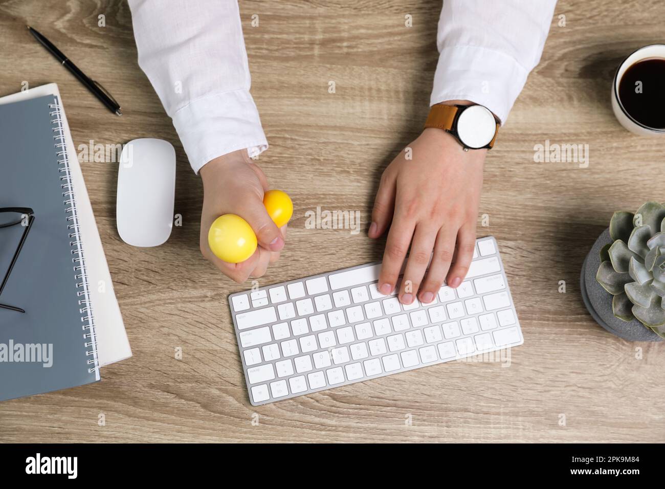 Man squeezing yellow stress ball while typing on computer keyboard at ...