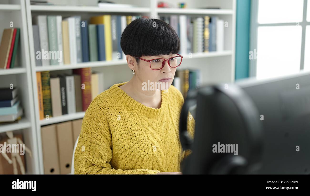 Young chinese woman student using computer studying at library ...
