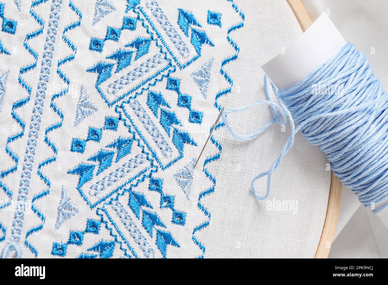 White fabric with blue Ukrainian national embroidery in hoop, needle ...
