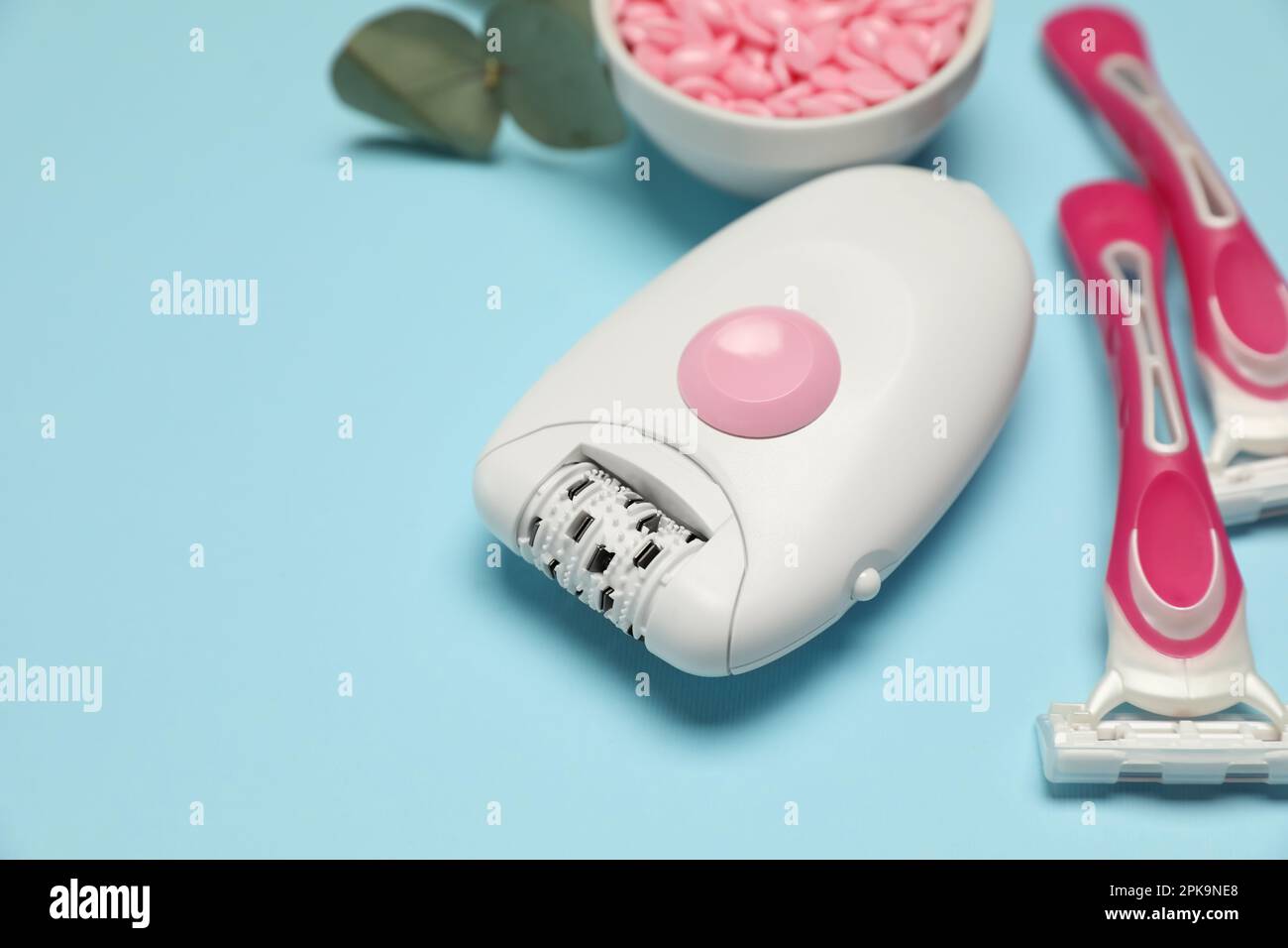 Epilator, razors and wax beads on light blue background Stock Photo - Alamy