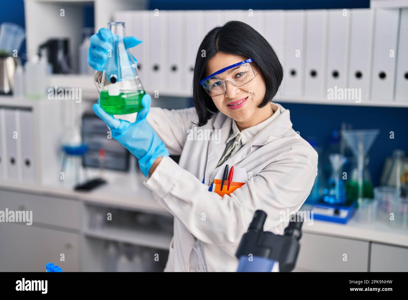 Young chinese woman scientist measuring liquid at laboratory Stock ...