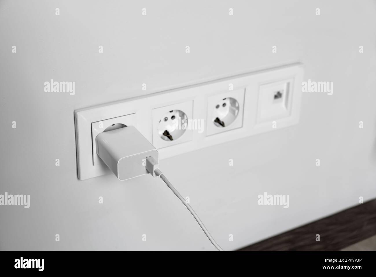Charger adapter plugged in power socket indoors, space for text Stock ...