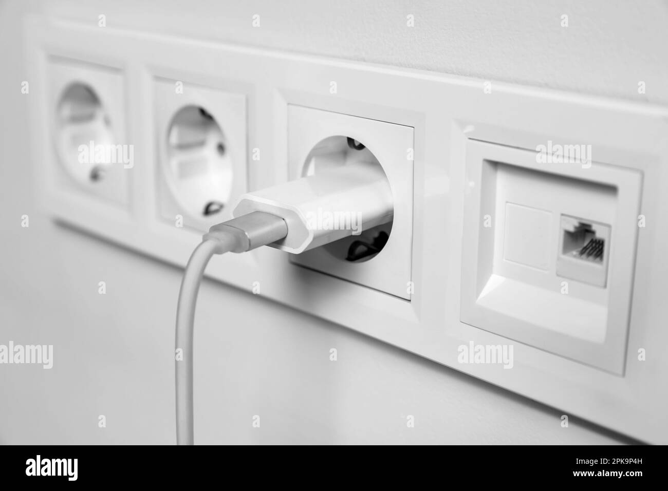 Charger adapter plugged in power socket indoors, closeup Stock Photo ...