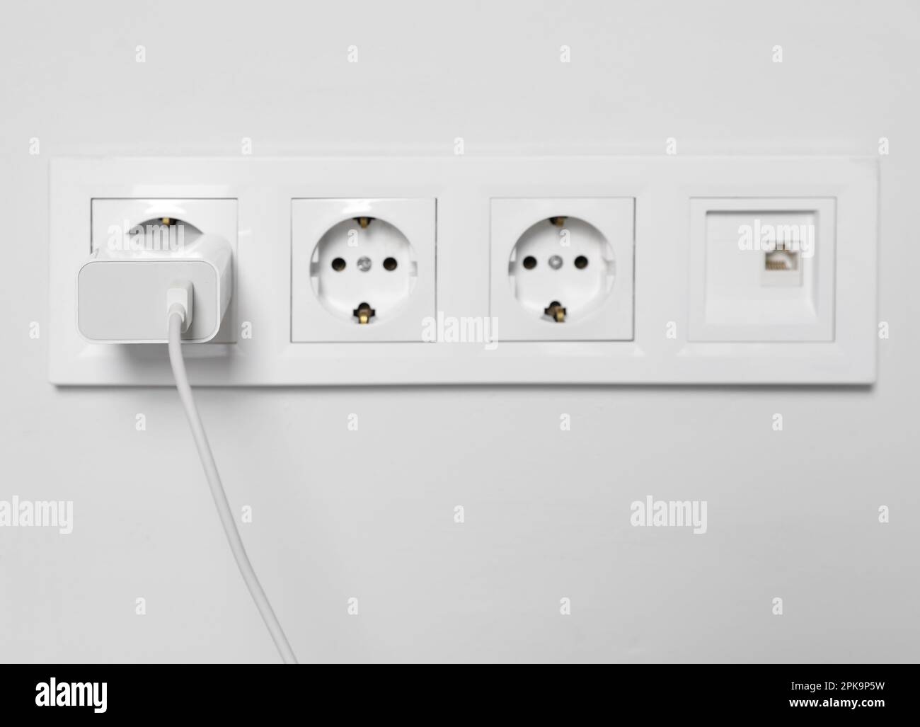 Charger adapter plugged in power socket indoors Stock Photo - Alamy