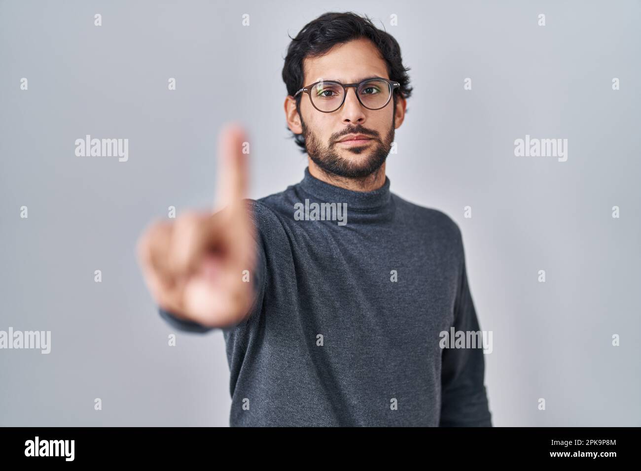 Handsome latin man standing over isolated background pointing with ...