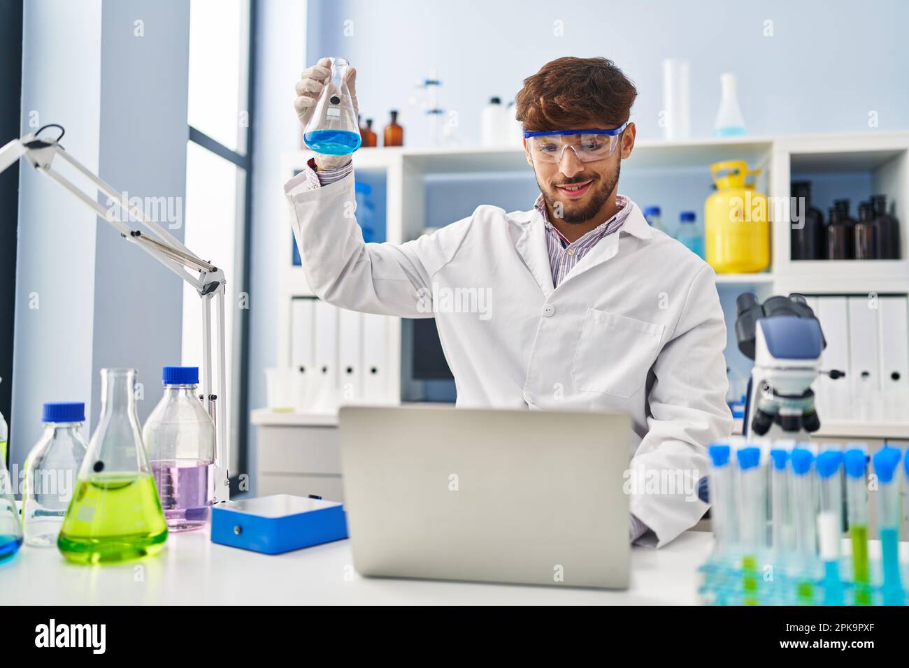 Young arab man scientist using laptop measuring liquid at laboratory Stock Photo - Alamy