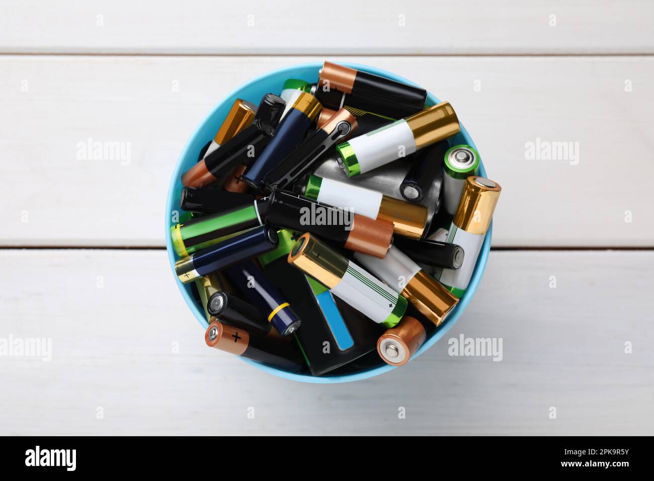 Used batteries in bucket on white wooden table, top view Stock Photo ...
