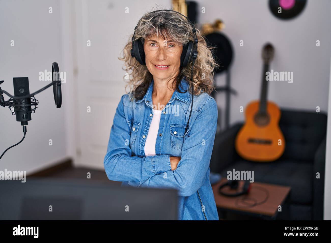 Middle age woman singer smiling with arms crossed gesture at music ...