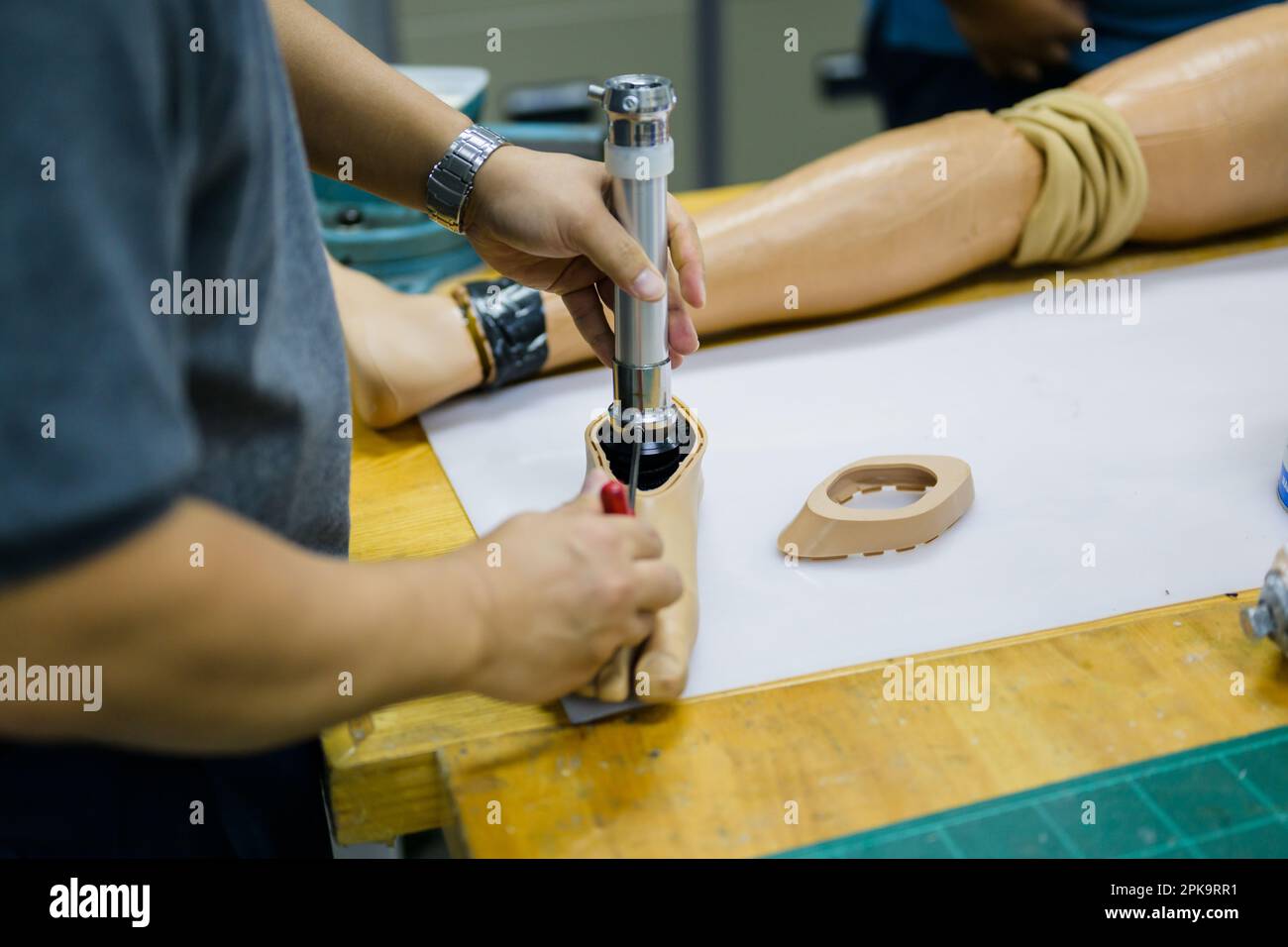 Male worker assembling parts of artificial leg in prosthetic workshop ...