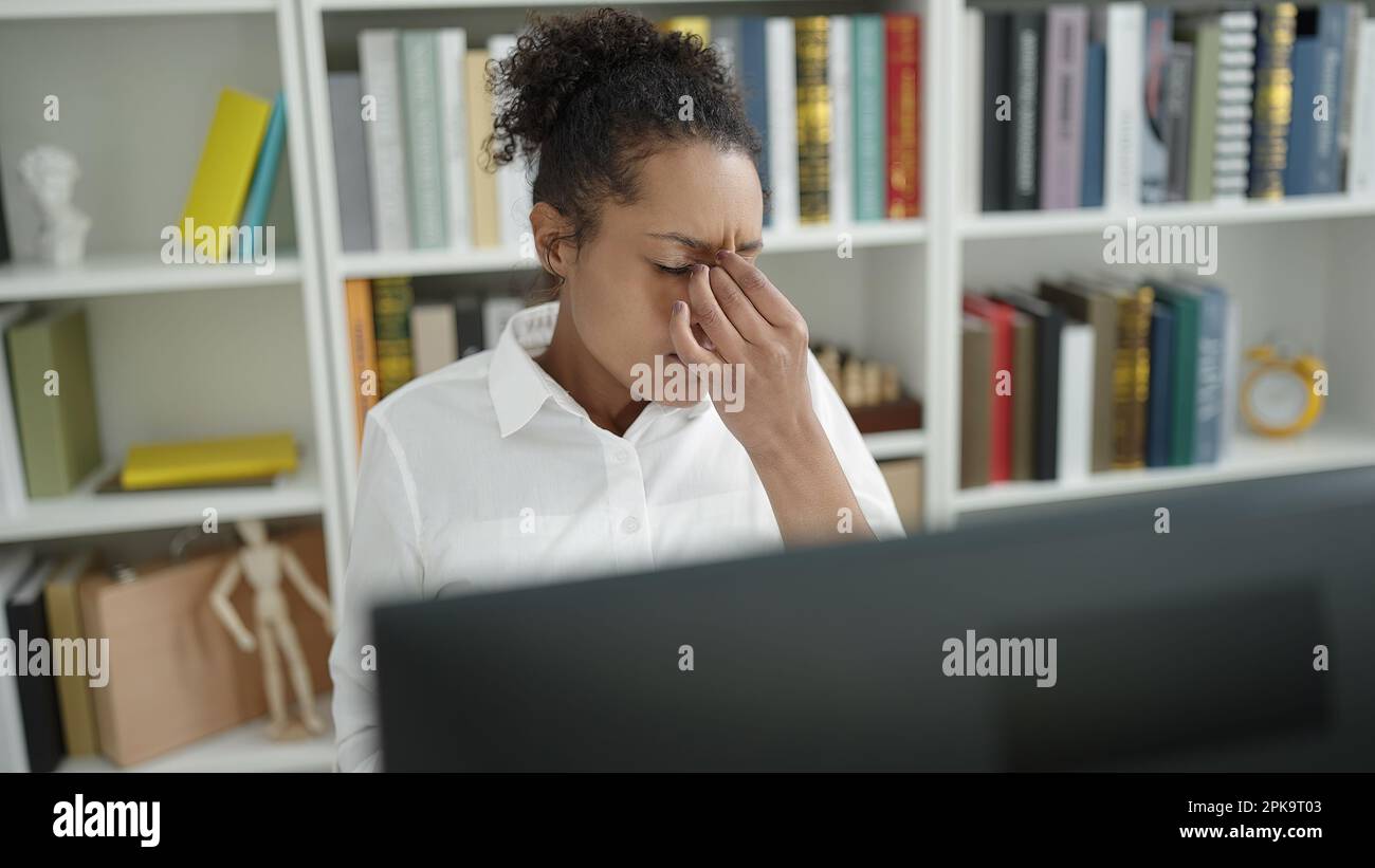 African american woman student using computer stressed at library ...