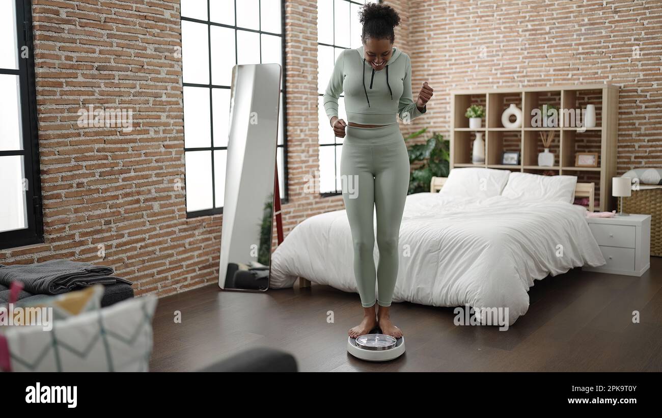 African american woman smiling confident measuring weight using ...