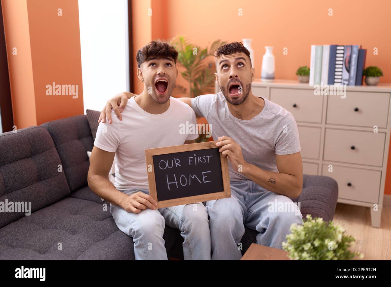 Homosexual gay couple holding blackboard with first home text angry and ...