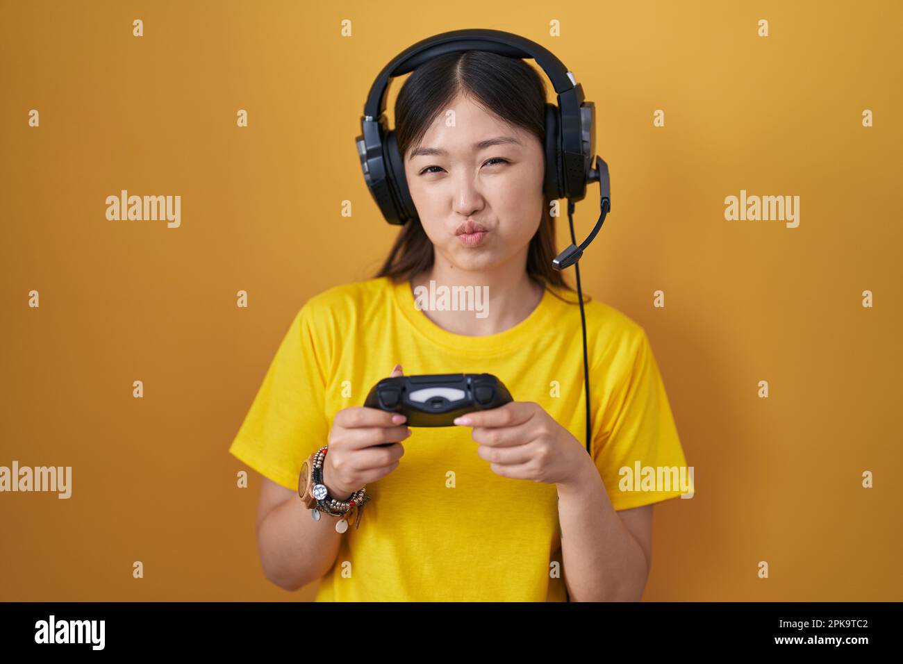 Chinese Young Woman Playing Video Game Holding Controller Puffing Cheeks With Funny Face Mouth