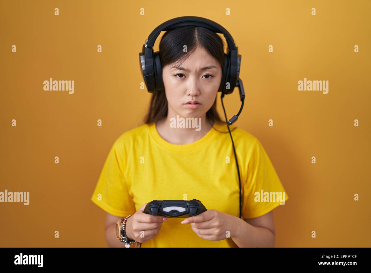 Chinese young woman playing video game holding controller looking ...