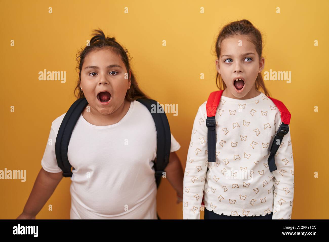 Two little girls friends wearing student backpack scared and amazed ...