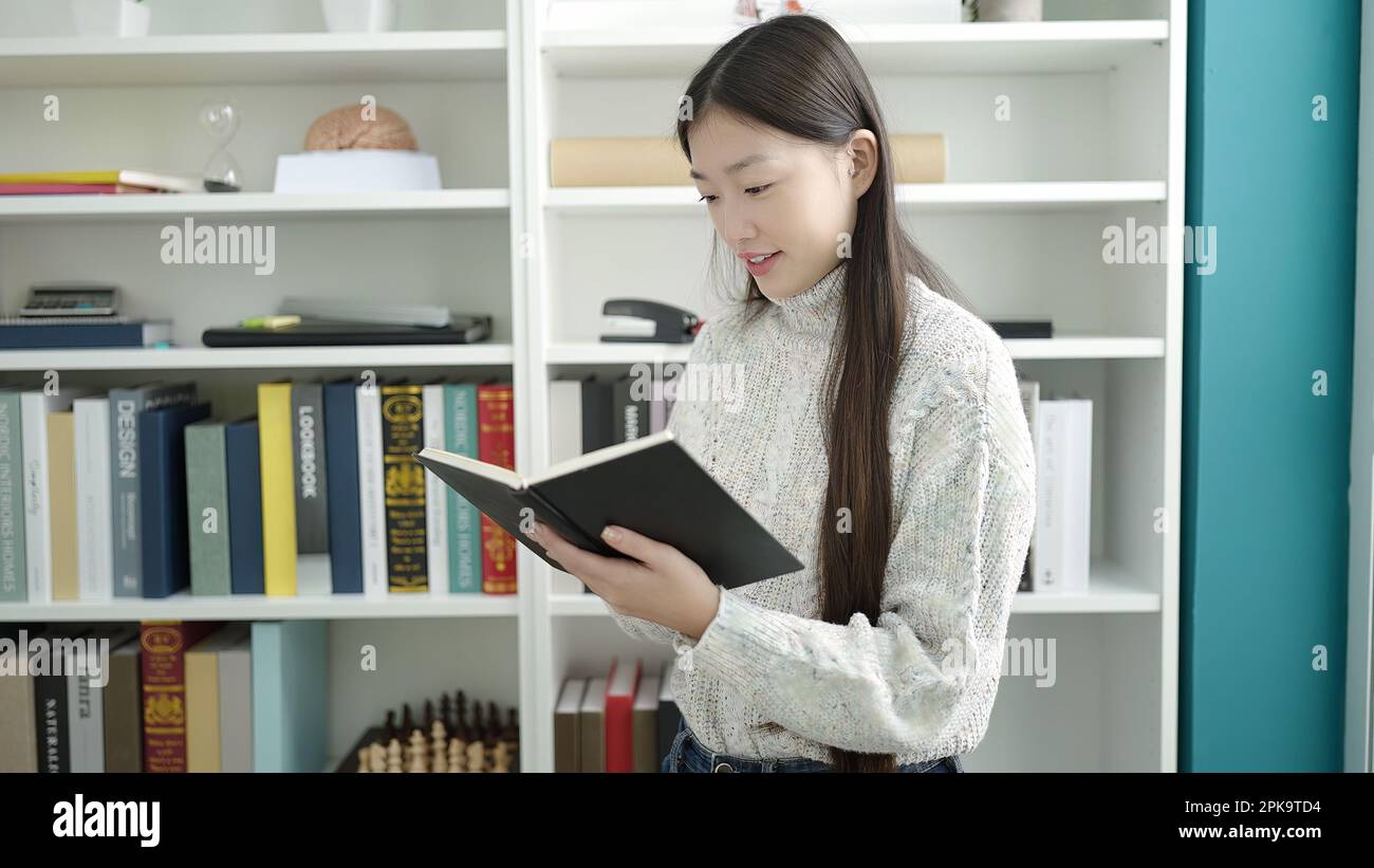 Young chinese woman student reading book studying at library university ...