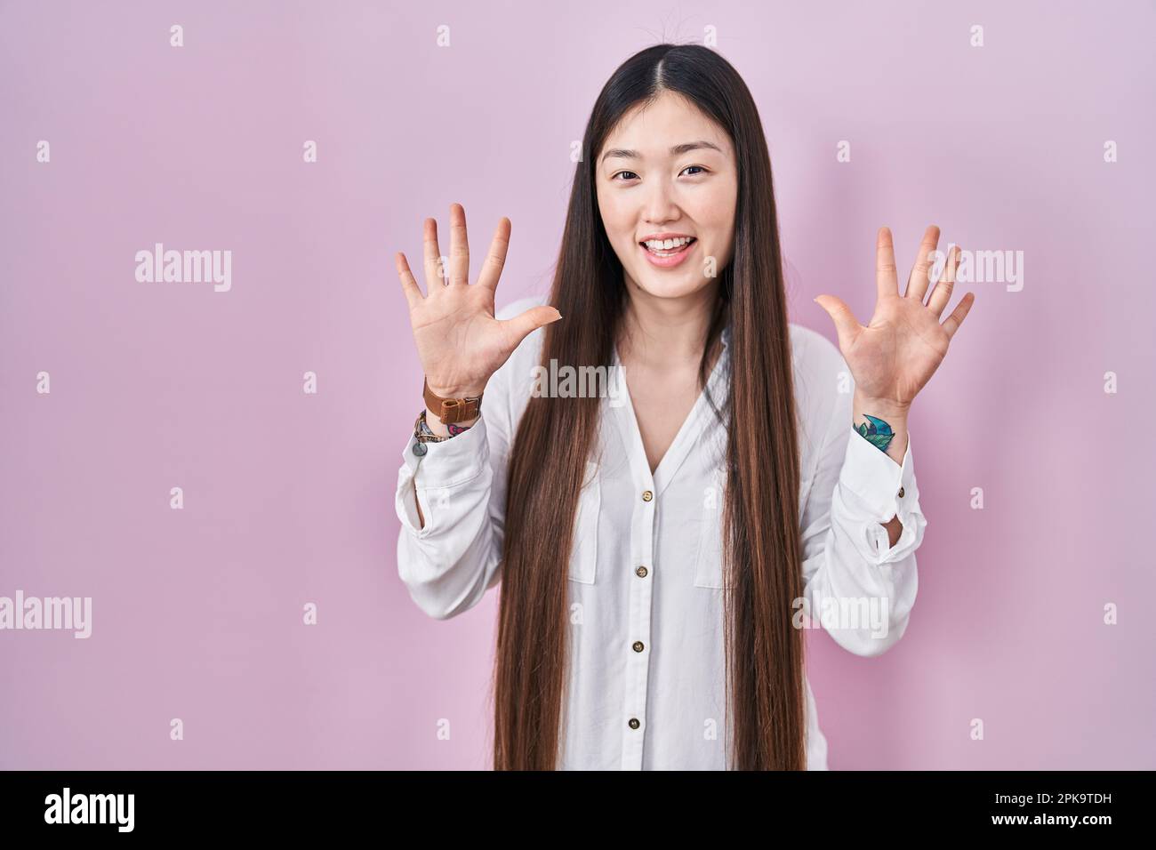 Chinese young woman standing over pink background showing and pointing ...