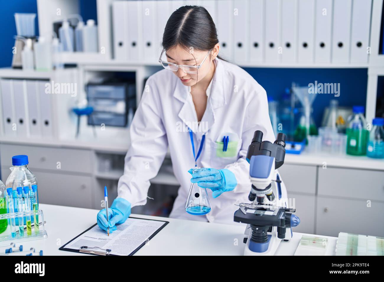 Chinese woman scientist measuring liquid writing on document at ...