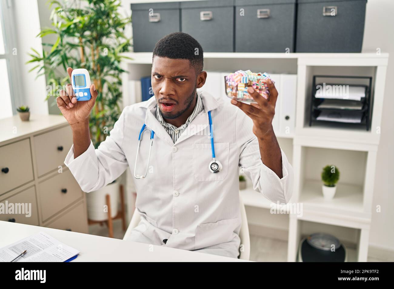 African american doctor man using glucose meter in shock face, looking ...