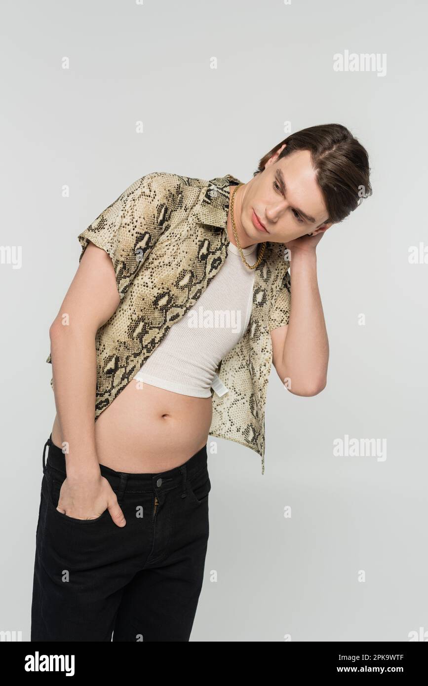 trendy bigender model in animal print blouse standing with hand in ...