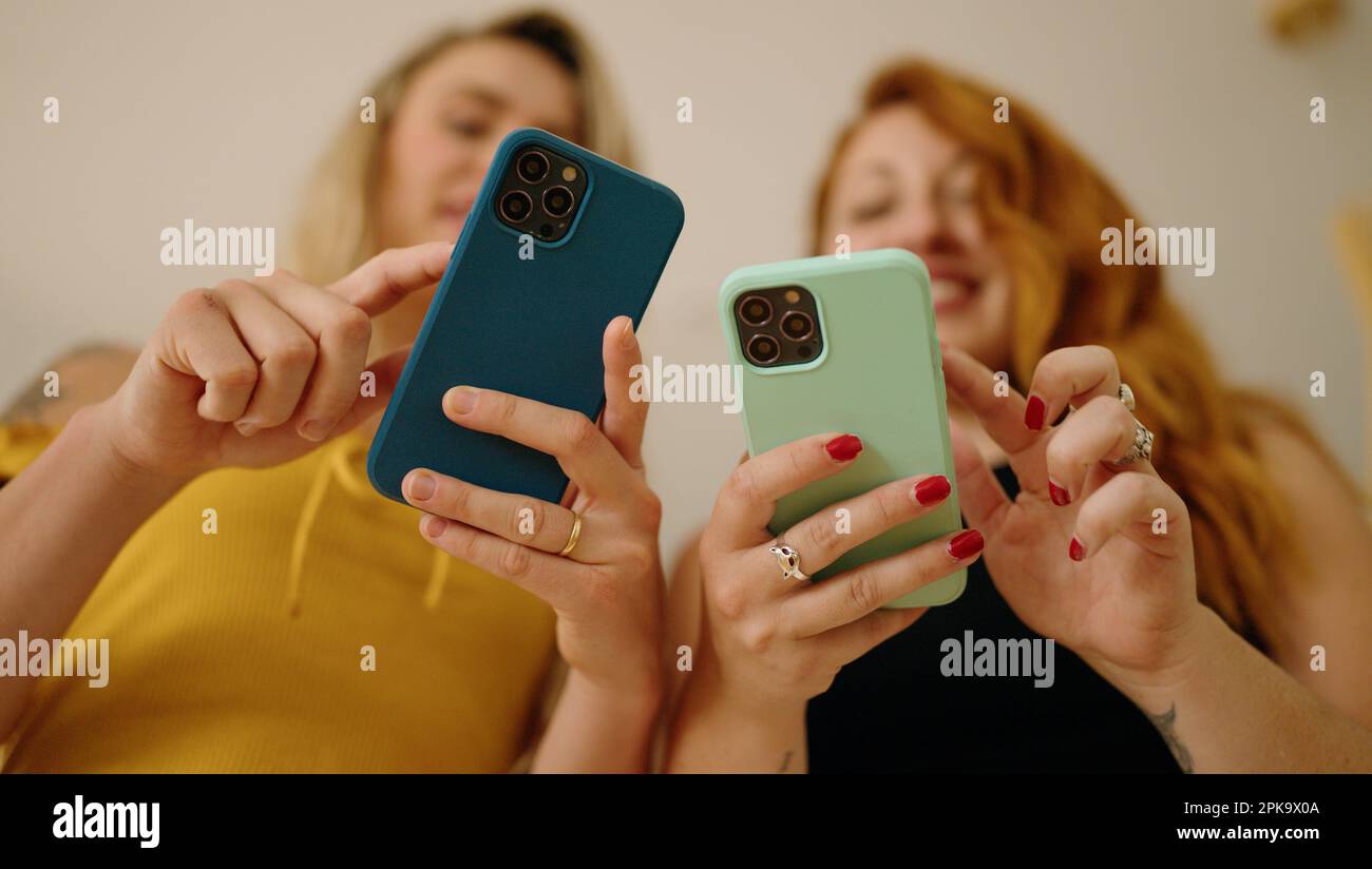 Two women using smartphones standing at home Stock Photo - Alamy