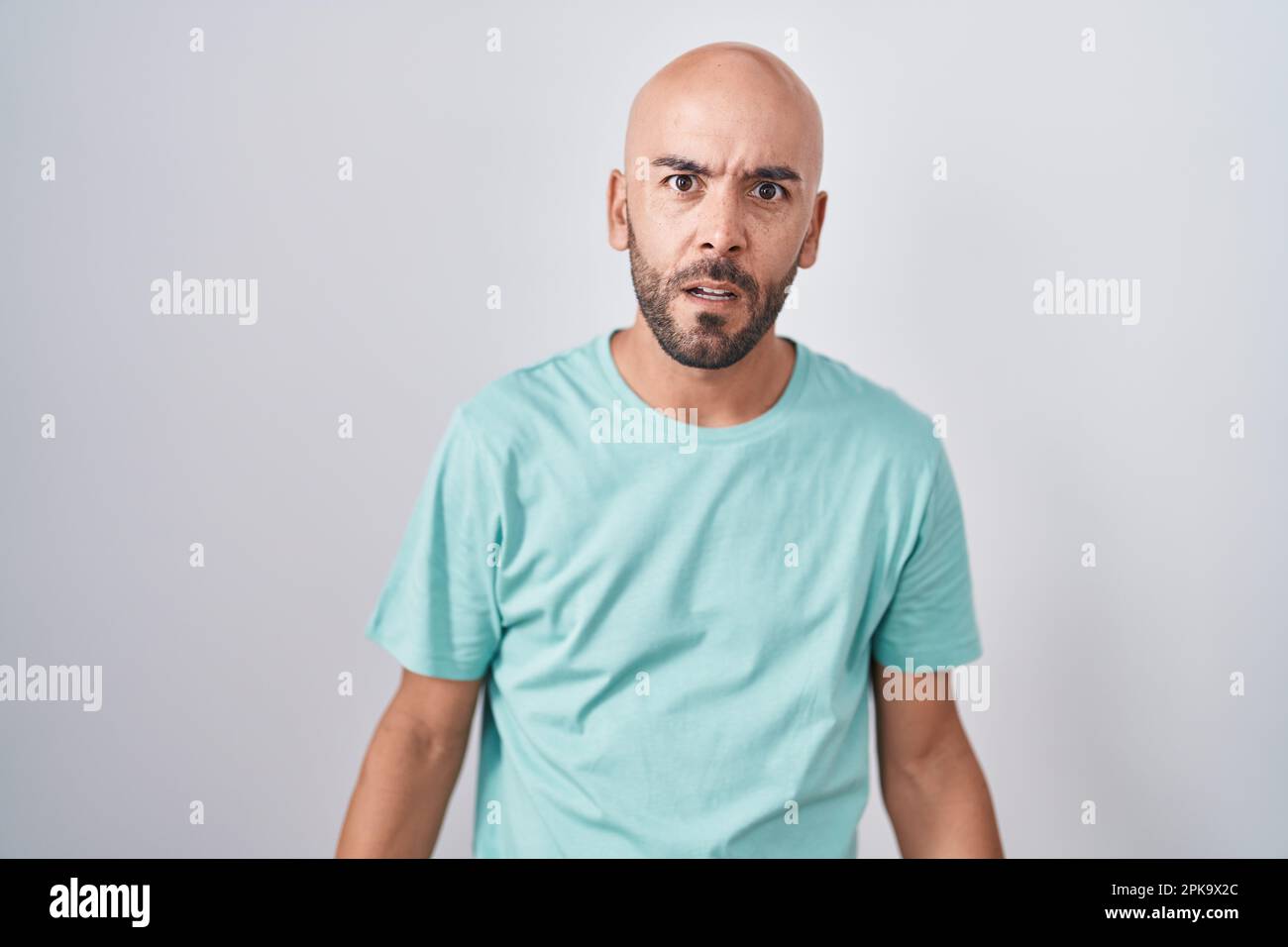 Middle age bald man standing over white background in shock face ...