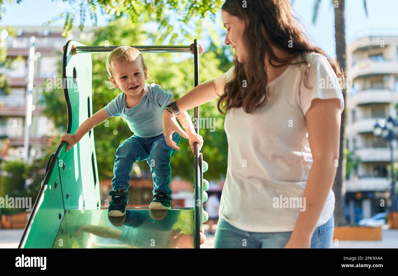 Mother and son smiling confident playing on slide at park playground Stock Photo - Alamy