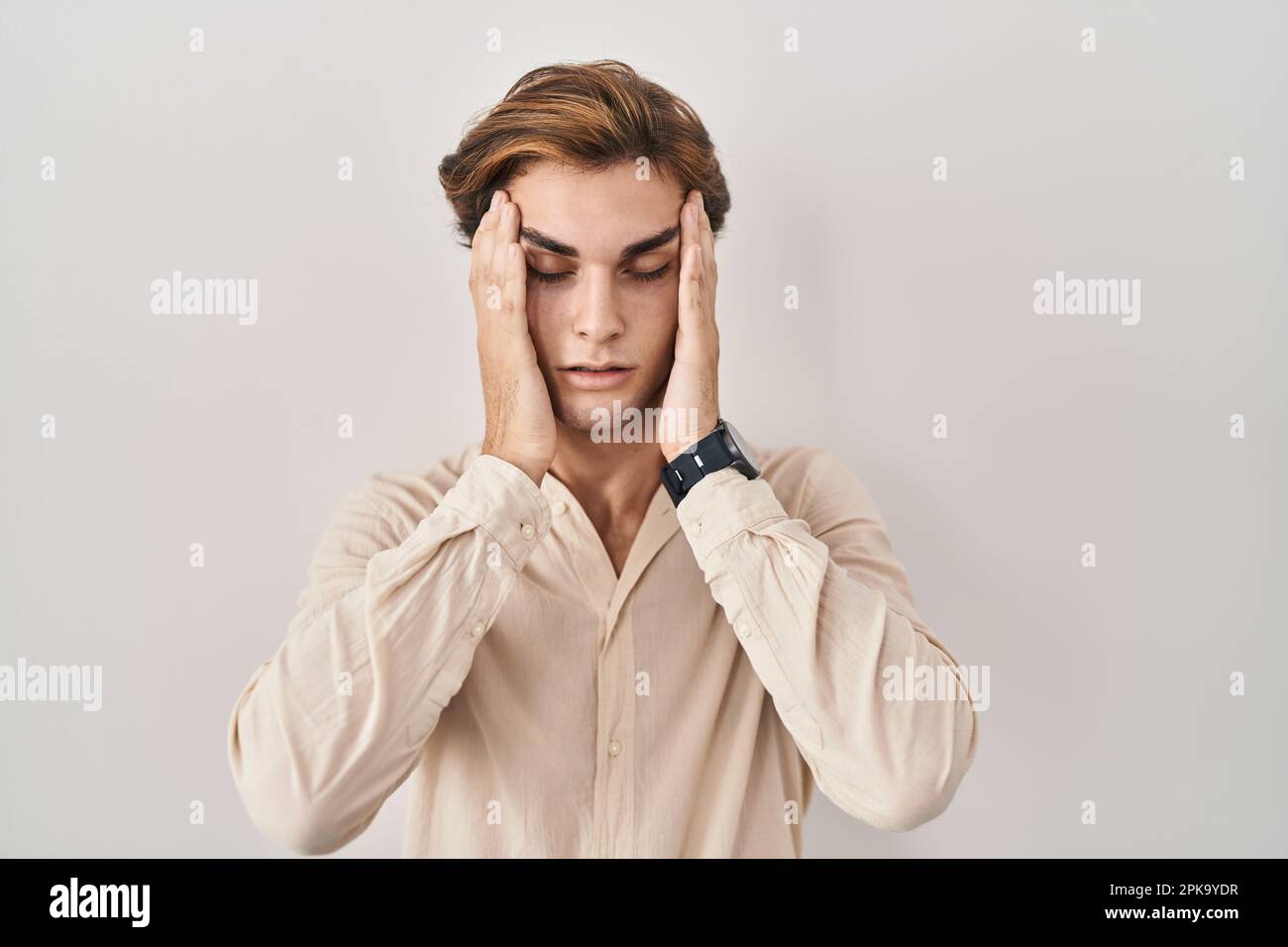 Young man standing over isolated background with hand on head, headache ...