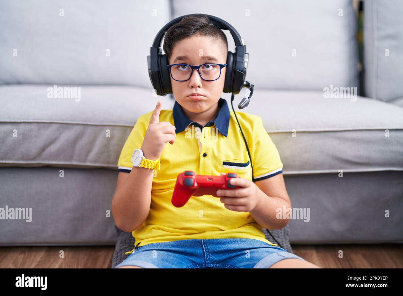 Young hispanic kid playing video game holding controller wearing ...
