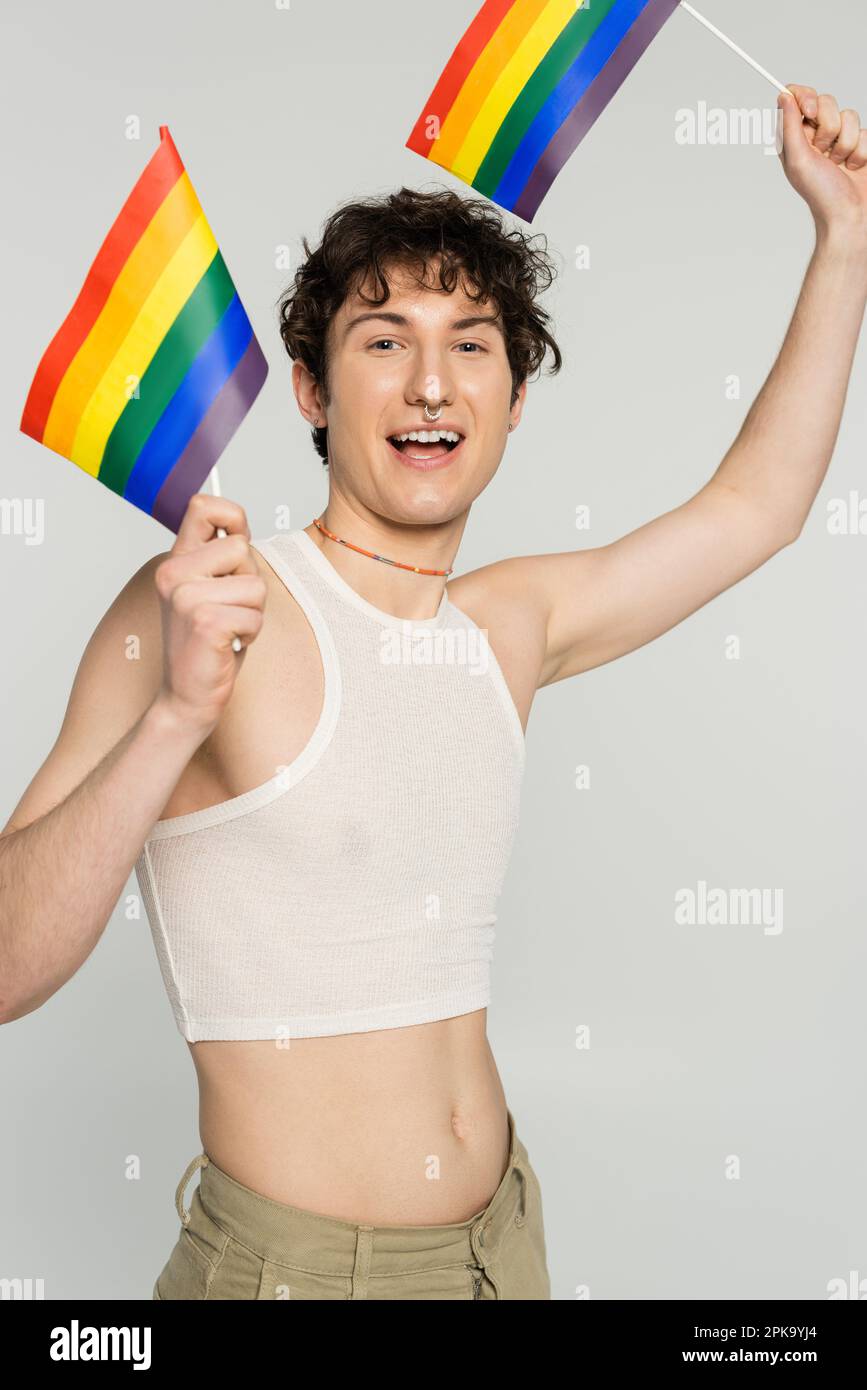 carefree bigender person in crop top standing with small lgbt flags ...