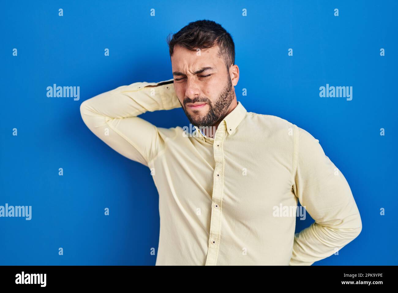 Handsome hispanic man standing over blue background suffering of neck ...