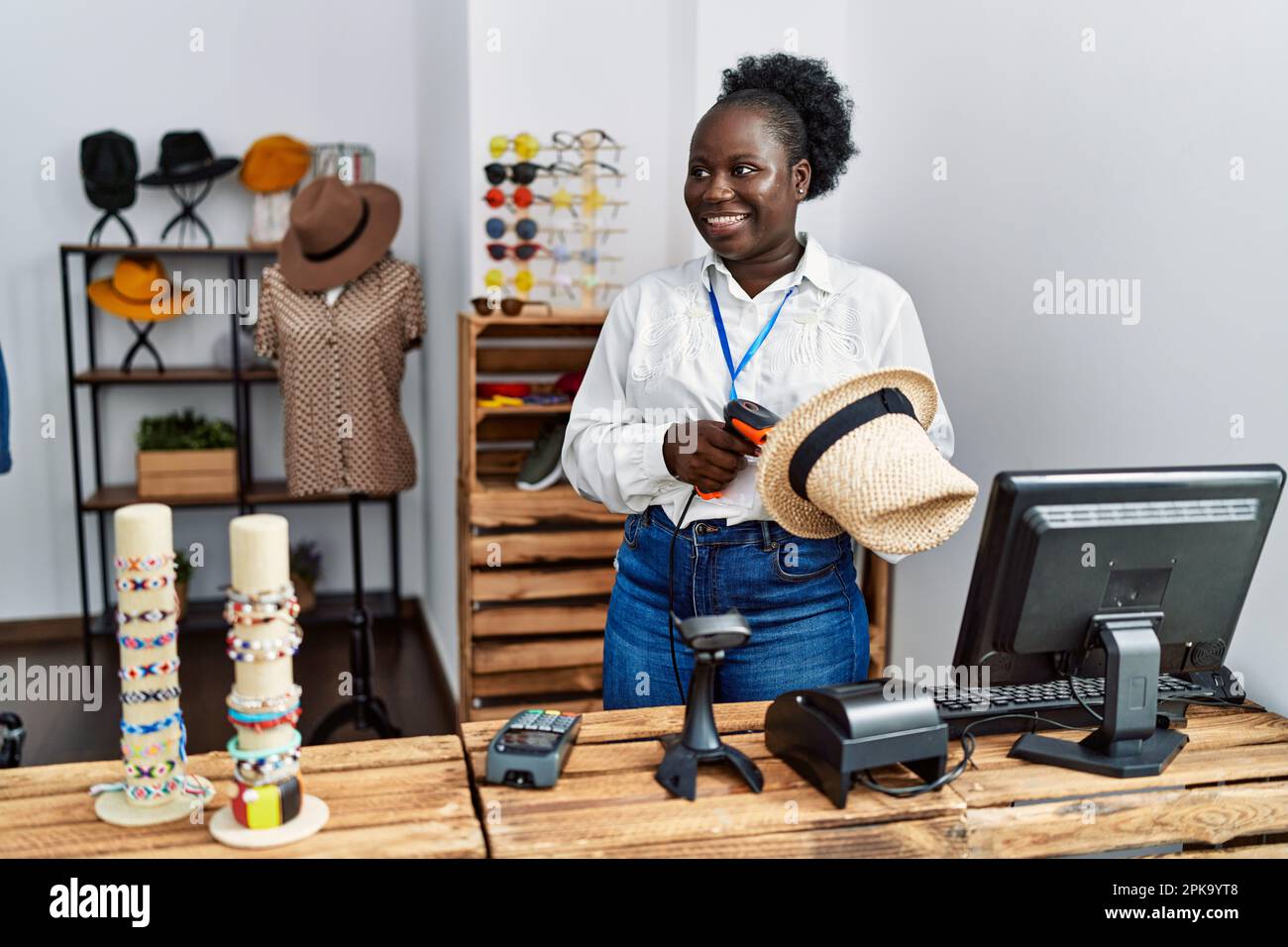 Young african american woman shopkeeper scanning hat using barcode ...