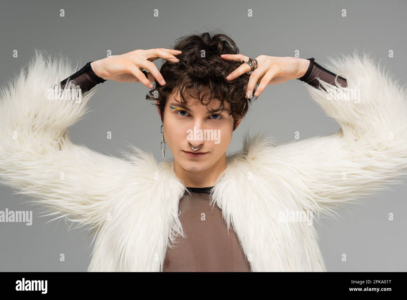 brunette nonbinary model in silver accessories and white faux fur ...