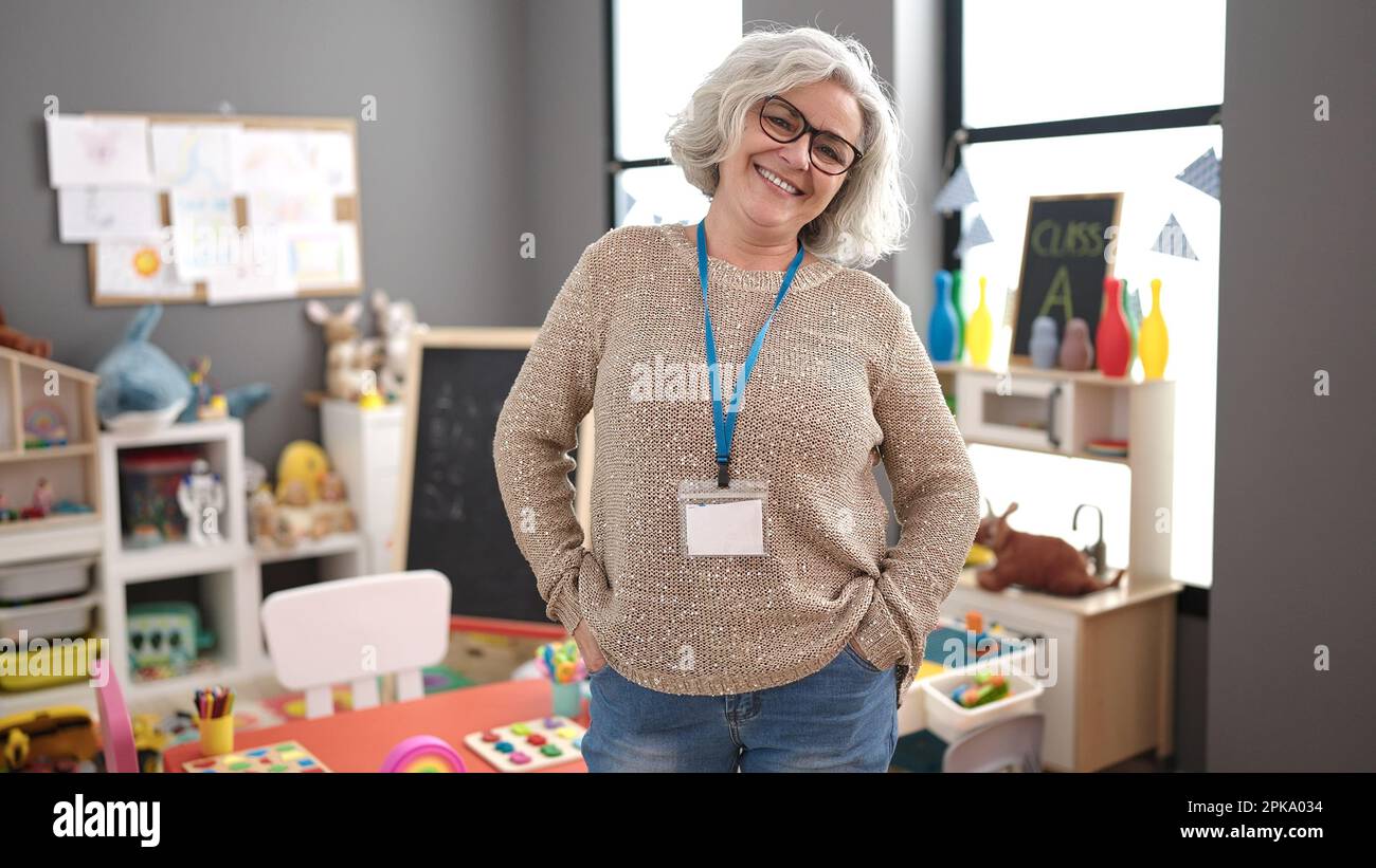 Middle age woman with grey hair preschool teacher smiling confident ...