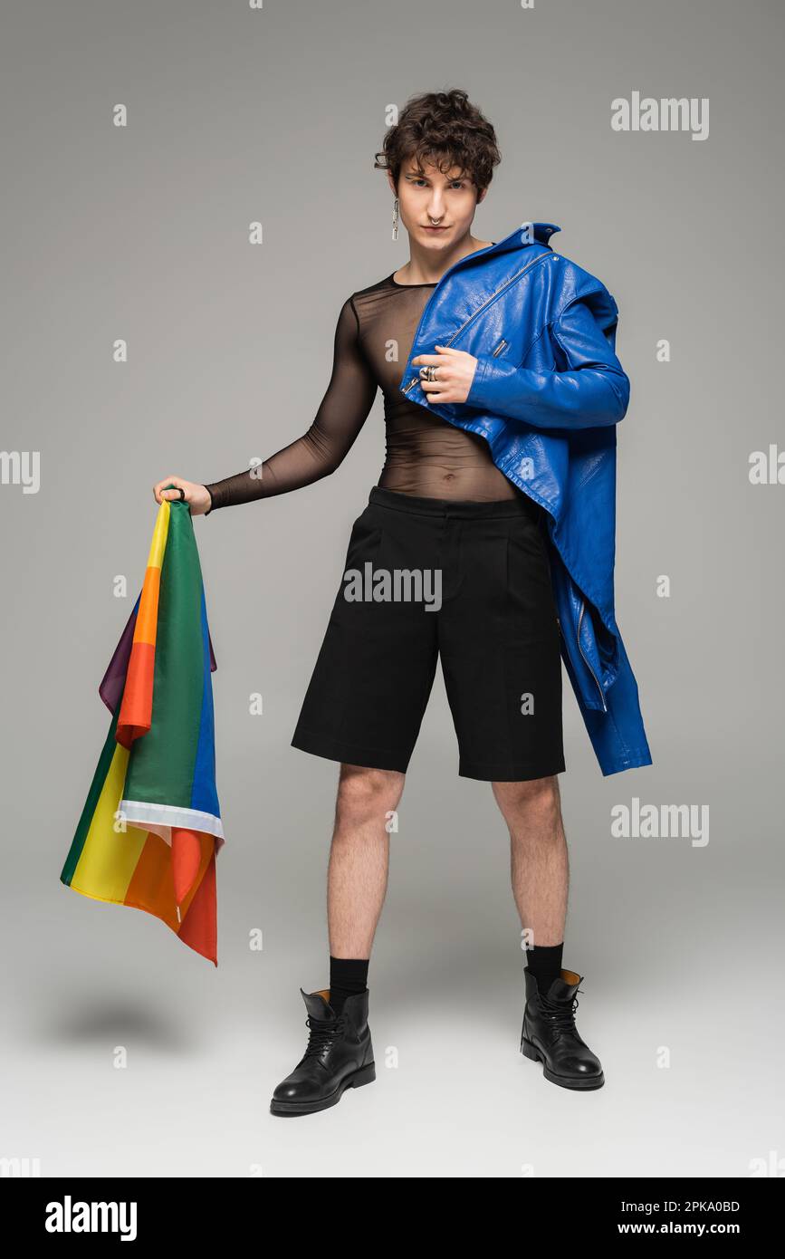 full length of trendy pangender person with blue leather jacket holding ...