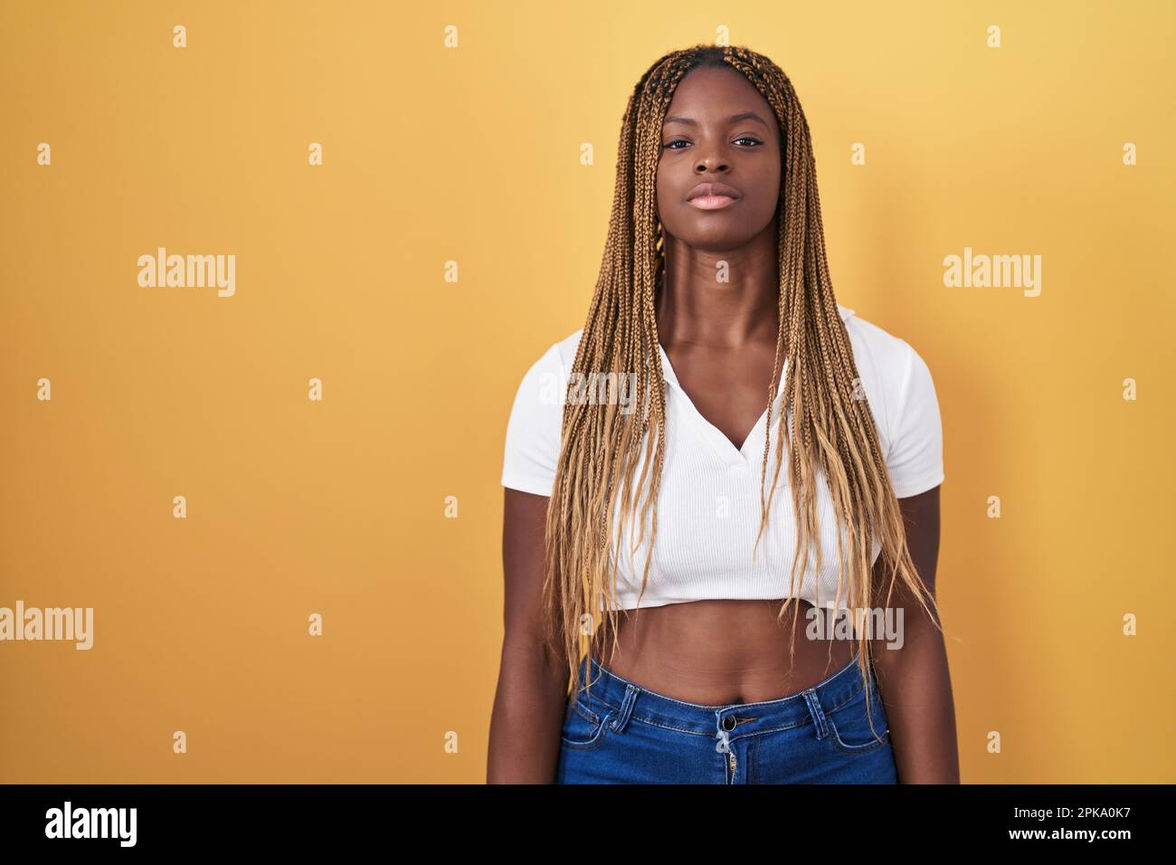 African american woman with braided hair standing over yellow ...