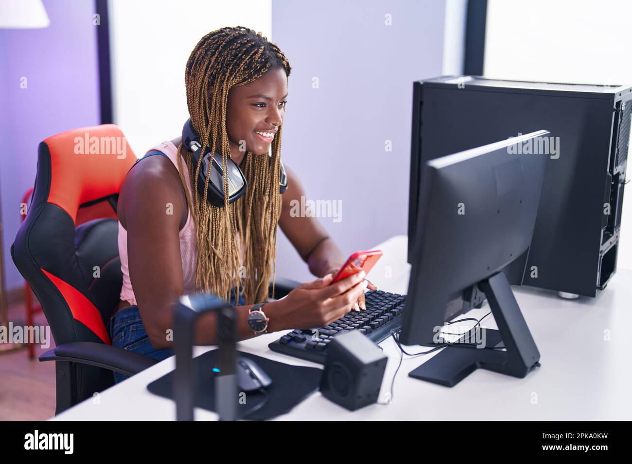 African american woman streamer using computer and smartphone at gaming ...
