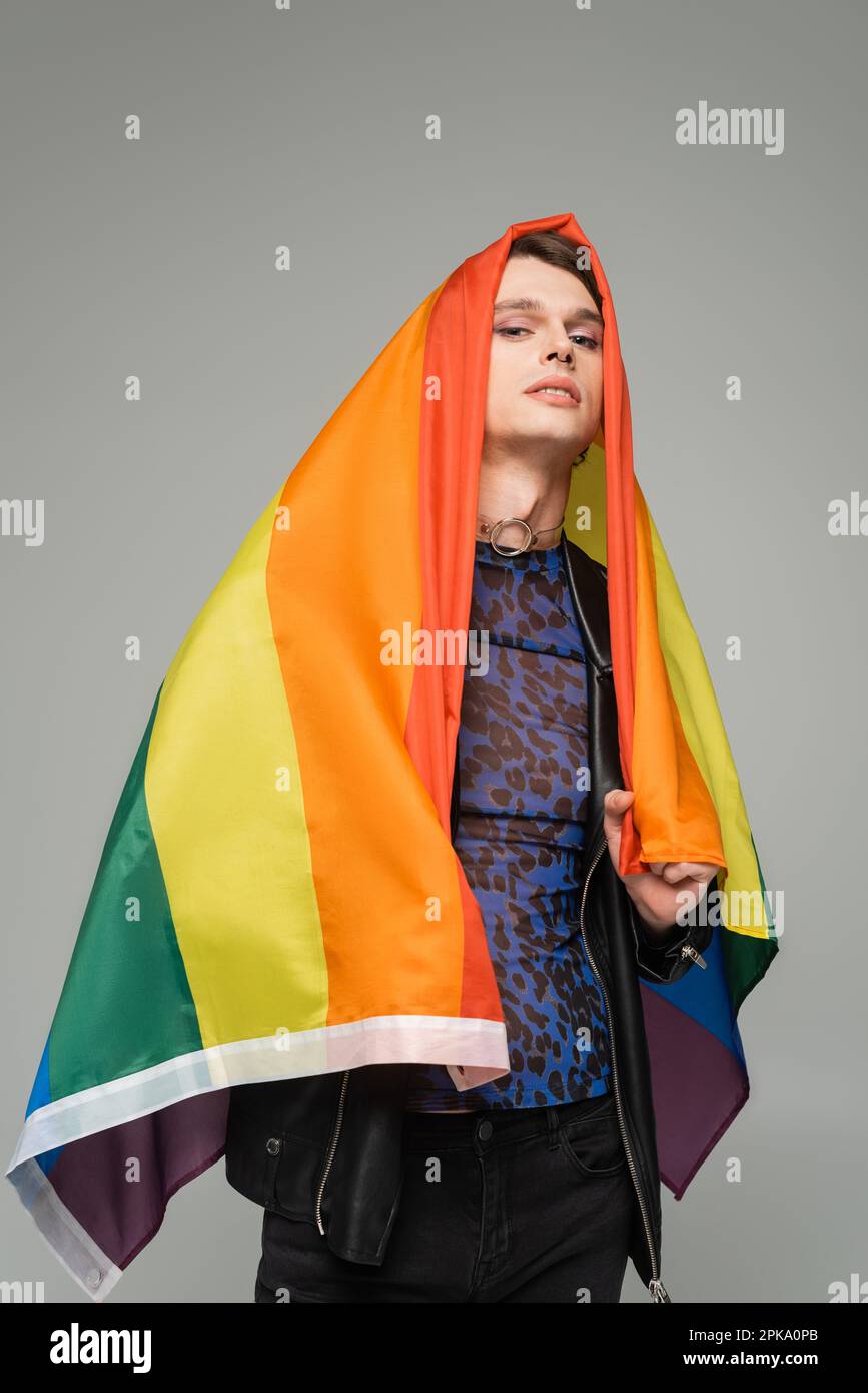 trendy pangender person covering himself with rainbow flag and looking ...