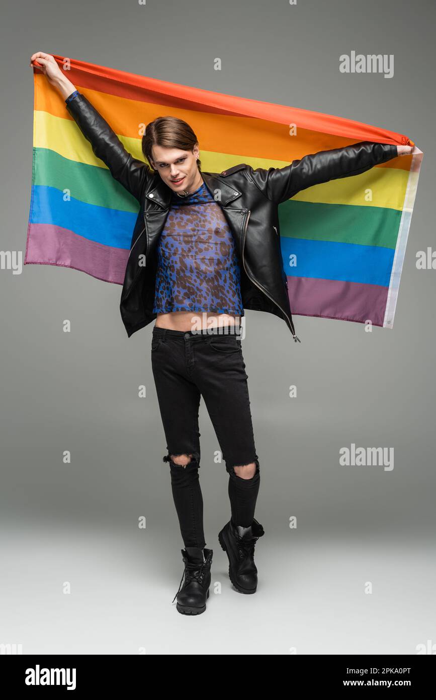 full length of smiling pangender person in black ripped pants and ...