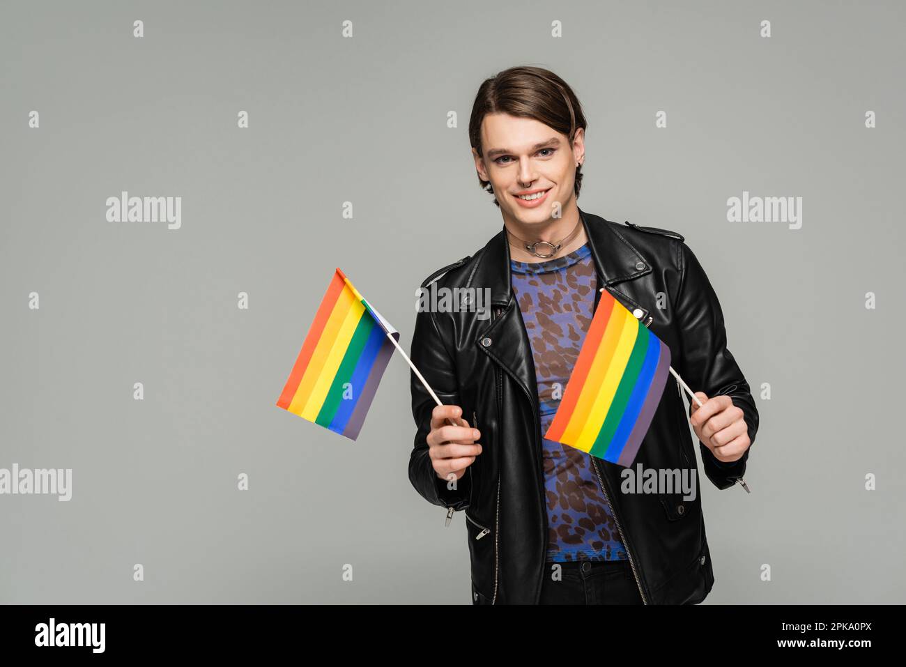 happy pangender person in black leather jacket holding small lgbt flags ...