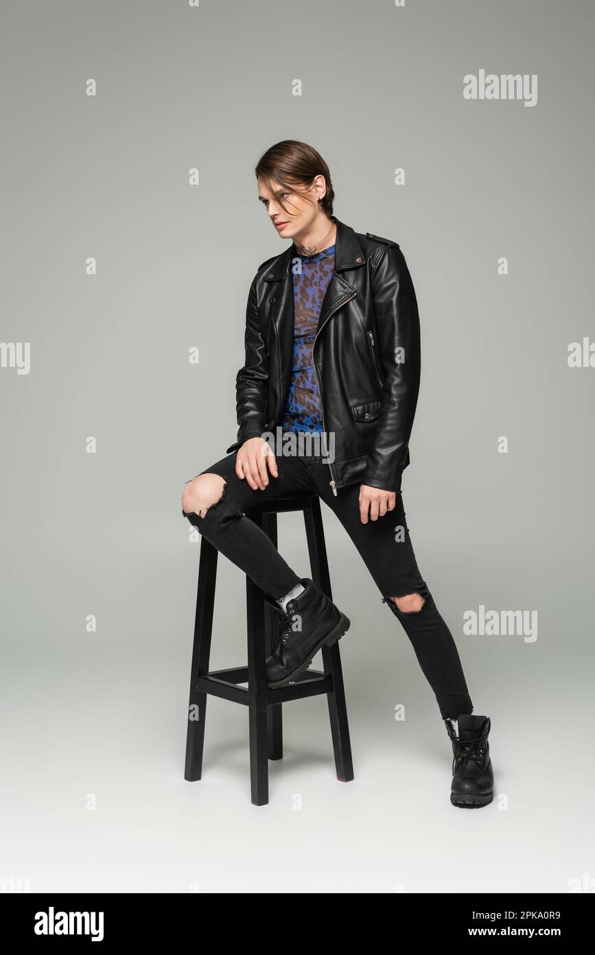 full length of bigender model in black leather jacket and ripped pants ...